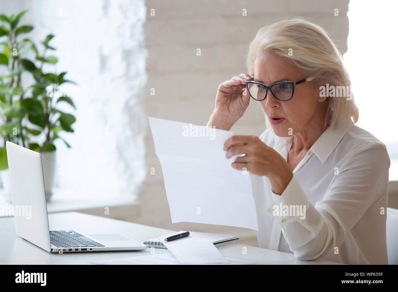 Confused senior businesswoman surprised reading paper letter Stock ...