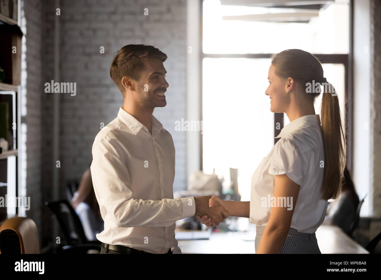 Smiling executive manager handshaking, greeting new hired employee ...