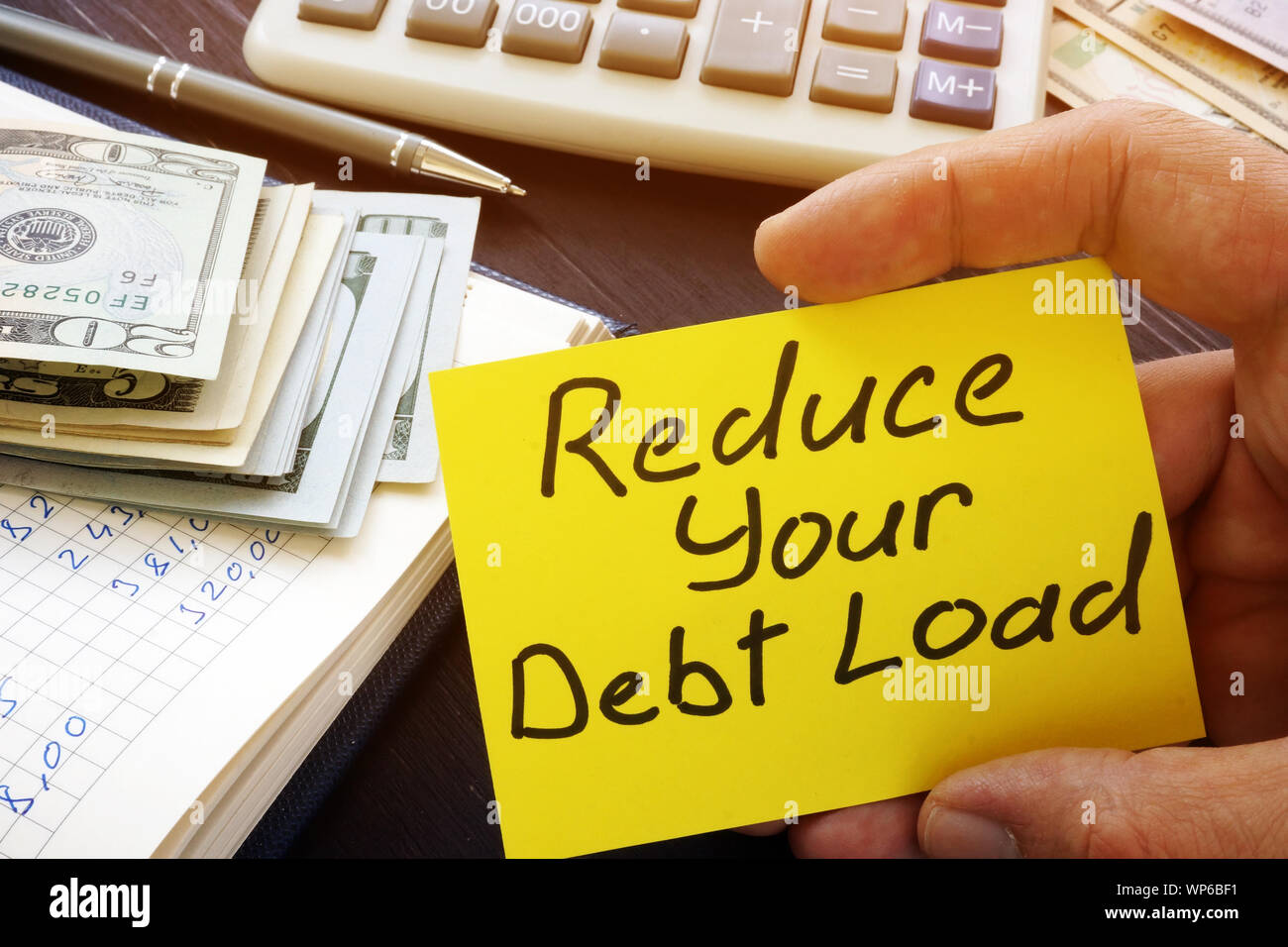 Man holds Reduce your debt load sign Stock Photo - Alamy