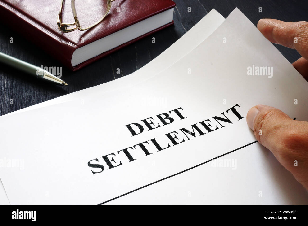 Hand is holding Debt Settlement documents Stock Photo - Alamy