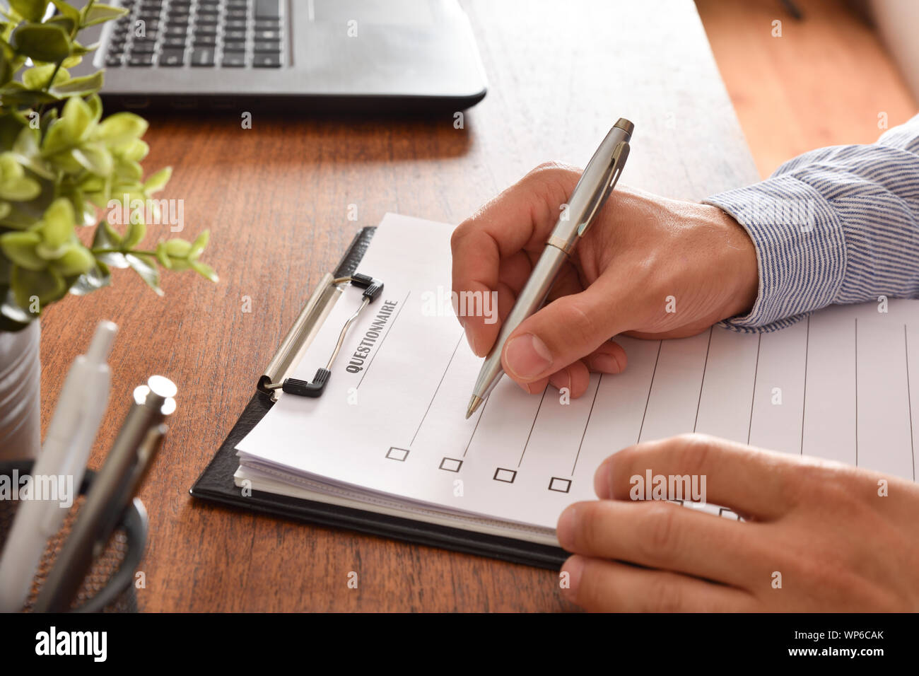 Man filling out a questionnaire on a wooden table. Horizontal ...