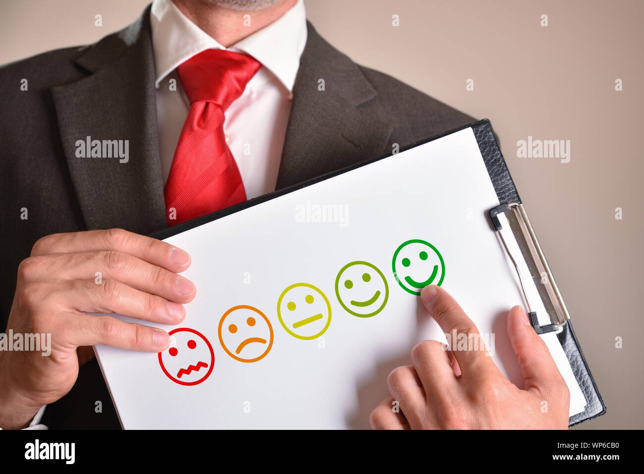 Man in a suit with a tie showing happy face emoticons drawn on a sheet ...