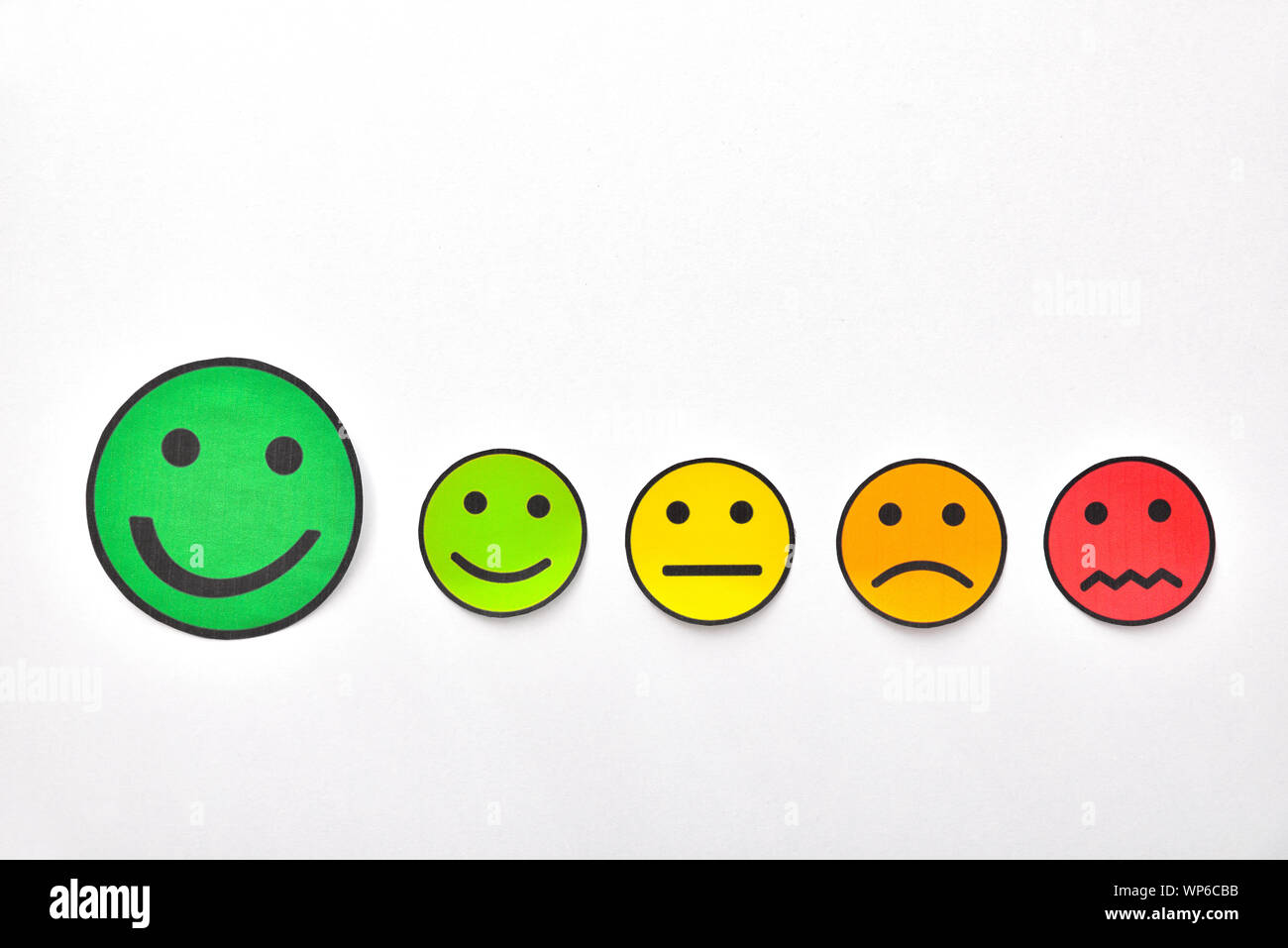 Paper face cutouts on white table highlighting positive rating ...