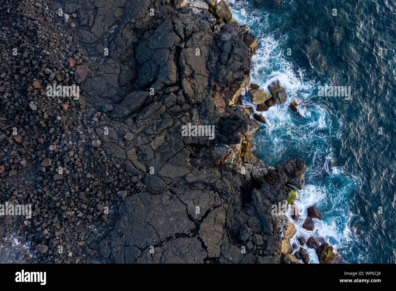 aerial image showing the typical black lava basalt coastline of Ilha do ...