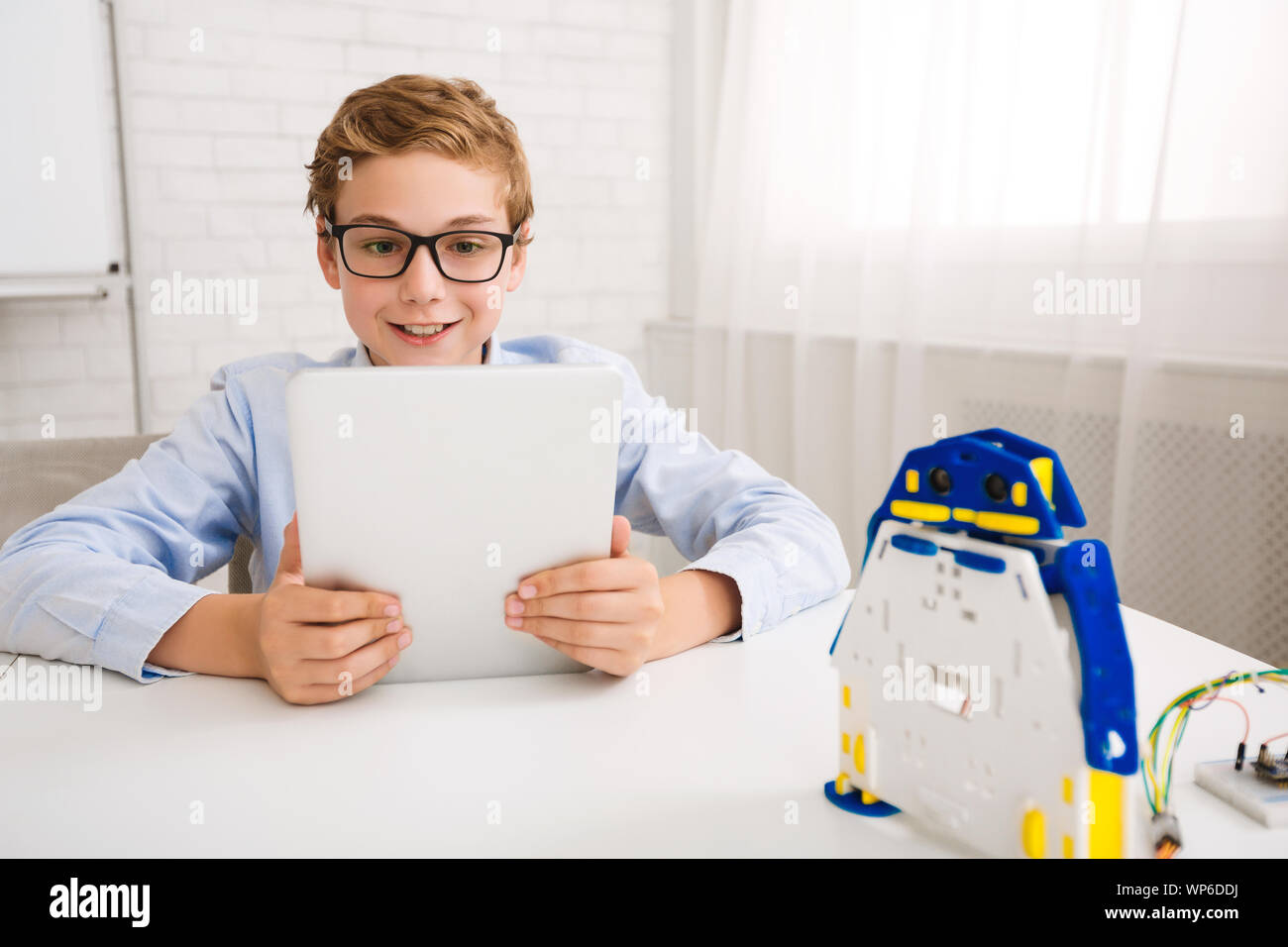Boy programming robot with digital tablet in class Stock Photo - Alamy