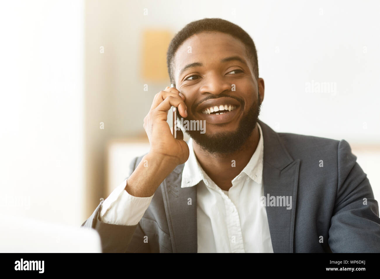 Positive african worker talking on phone with happy face expression ...