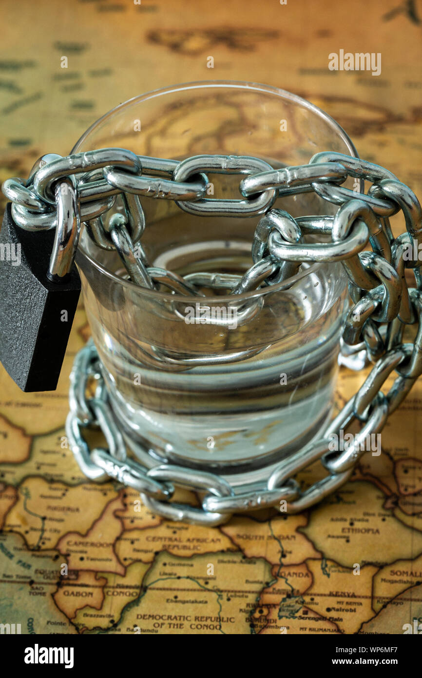 glass of water wrapped in a chain and closed with a padlock. World map ...