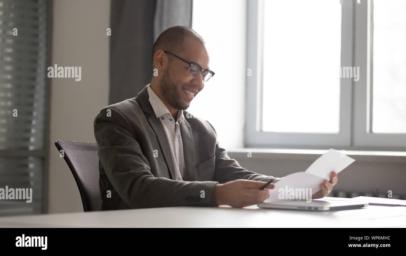 Happy african american male executive manager reviewing contract ...