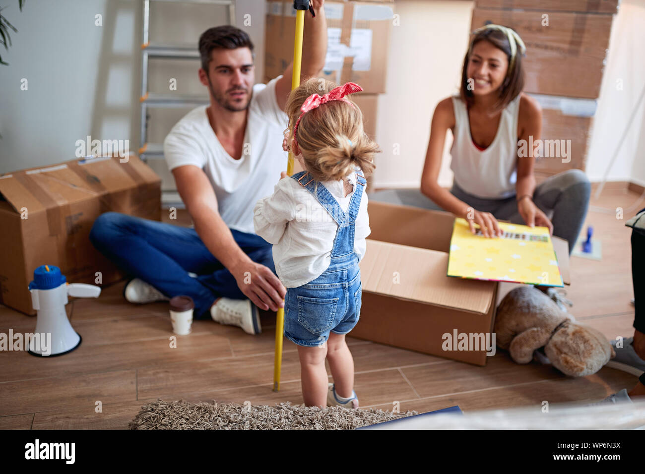 Happy child girl with parents moving in new home unpacking boxes Stock ...