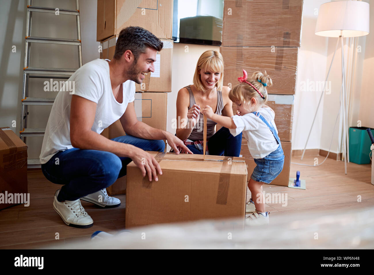 Happy young parents with child moving in new home unpacking boxes Stock ...