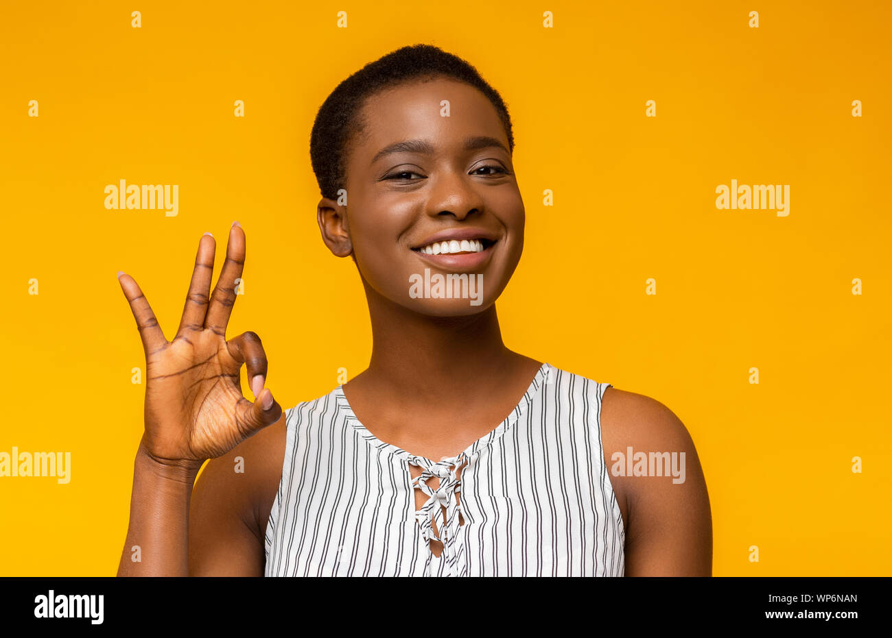 Happy black woman gesturing OK sign and smiling Stock Photo - Alamy