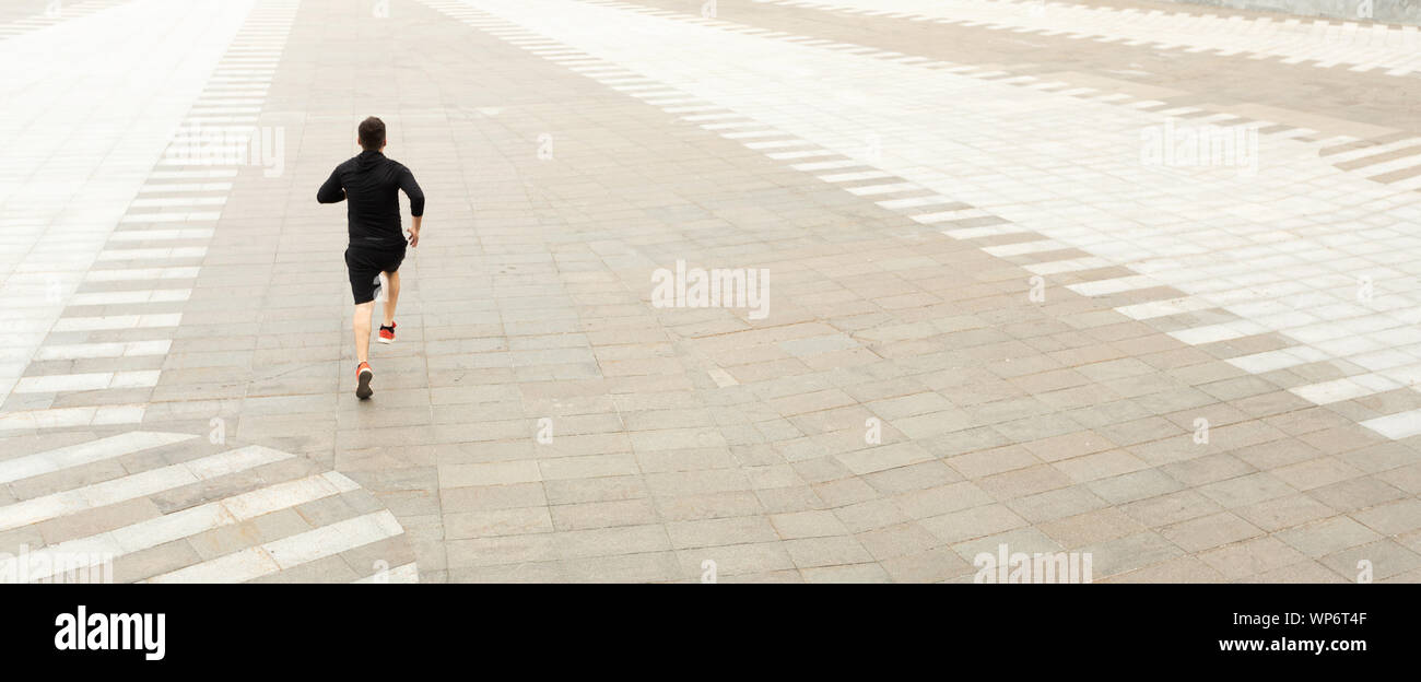 Rear view of male athlete running along city Stock Photo - Alamy