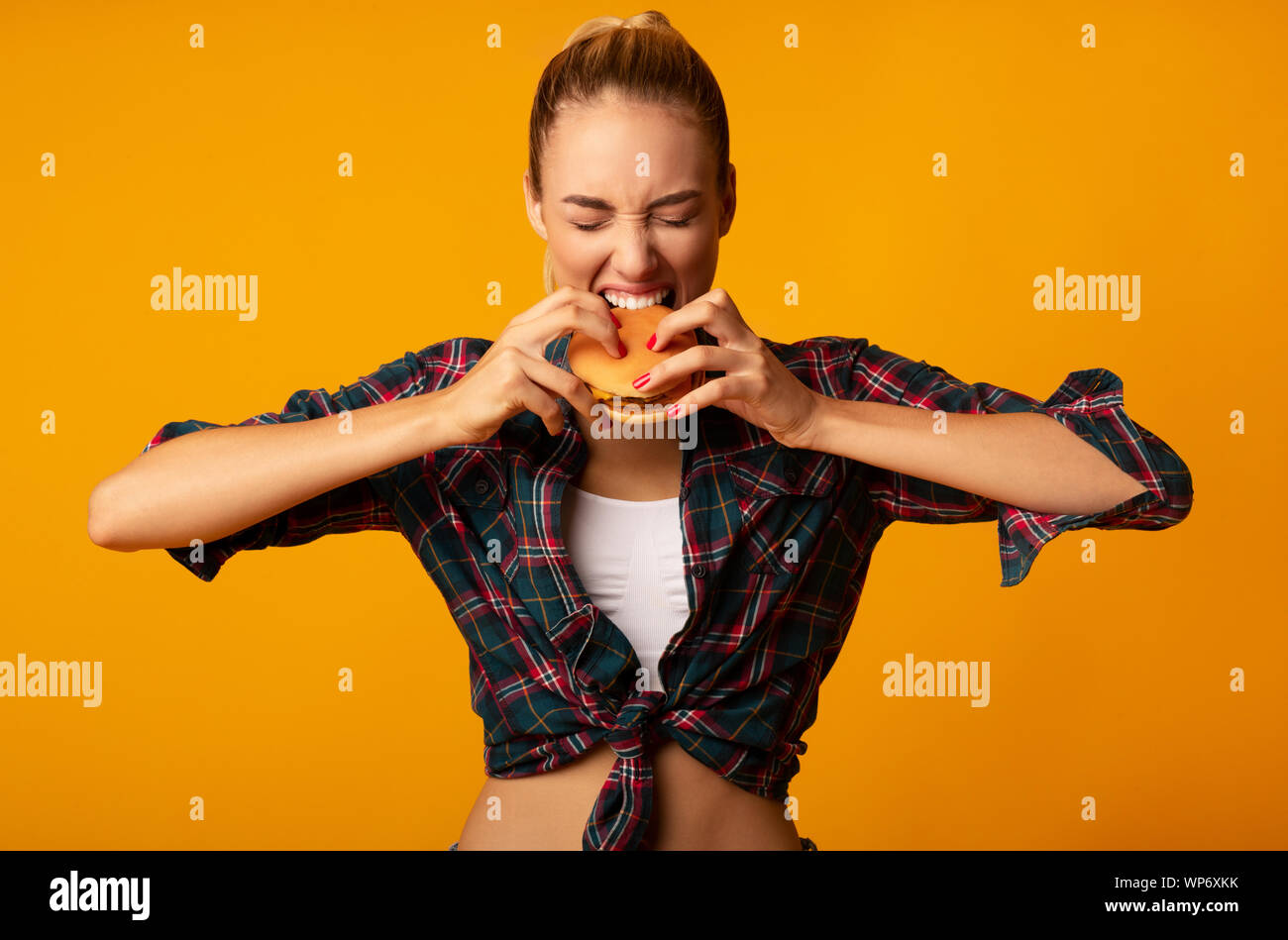 Sporty Girl Biting Burger On Yellow Background Stock Photo - Alamy
