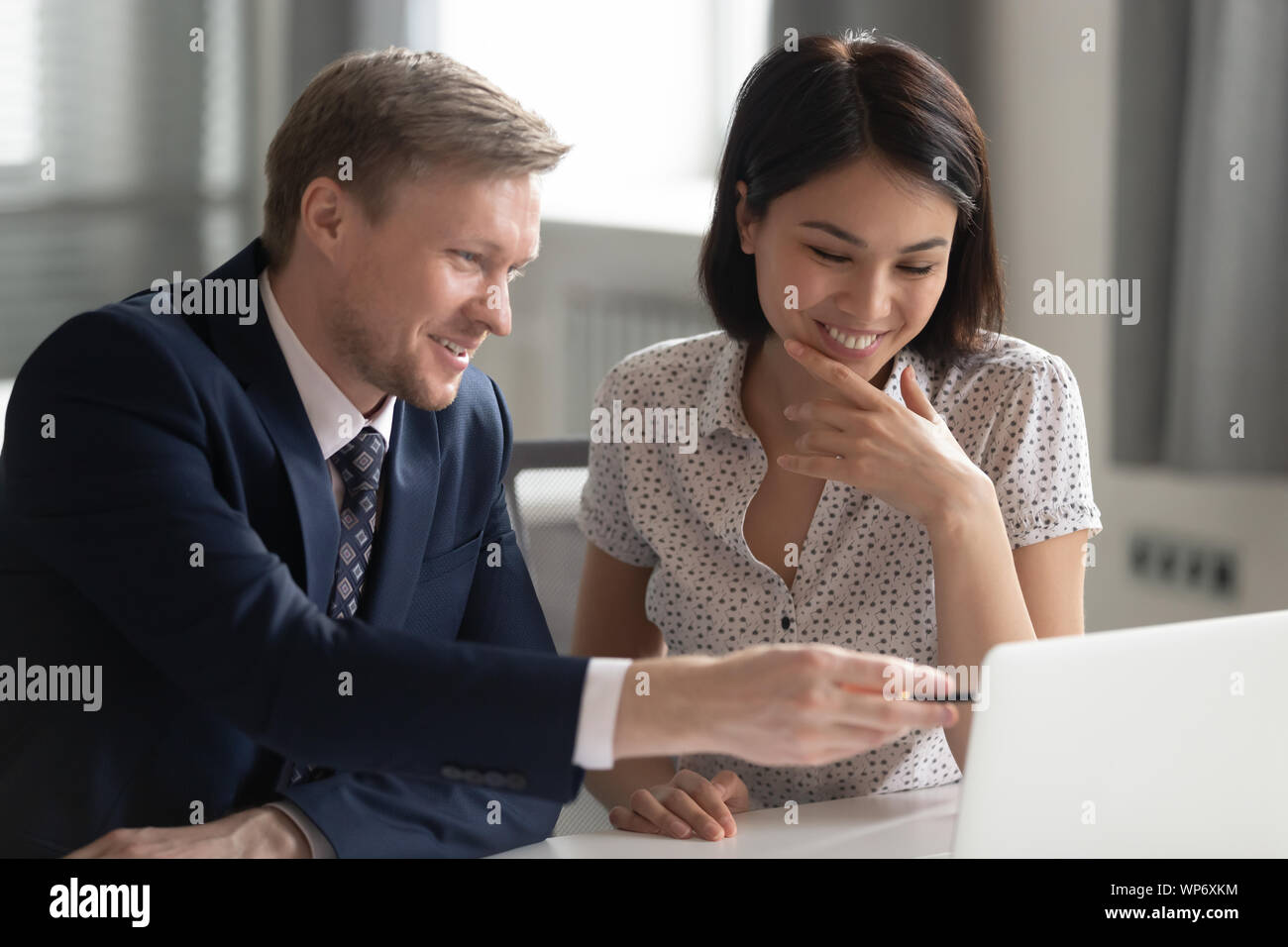 Smiling middle aged team leader helping korean female happy intern ...