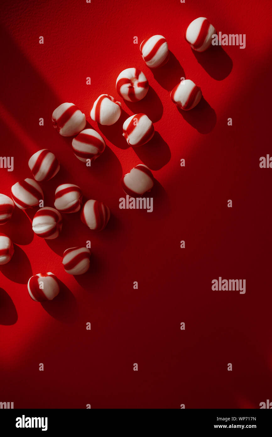 Peppermint candies on red background. Direct sun light, focus on ...