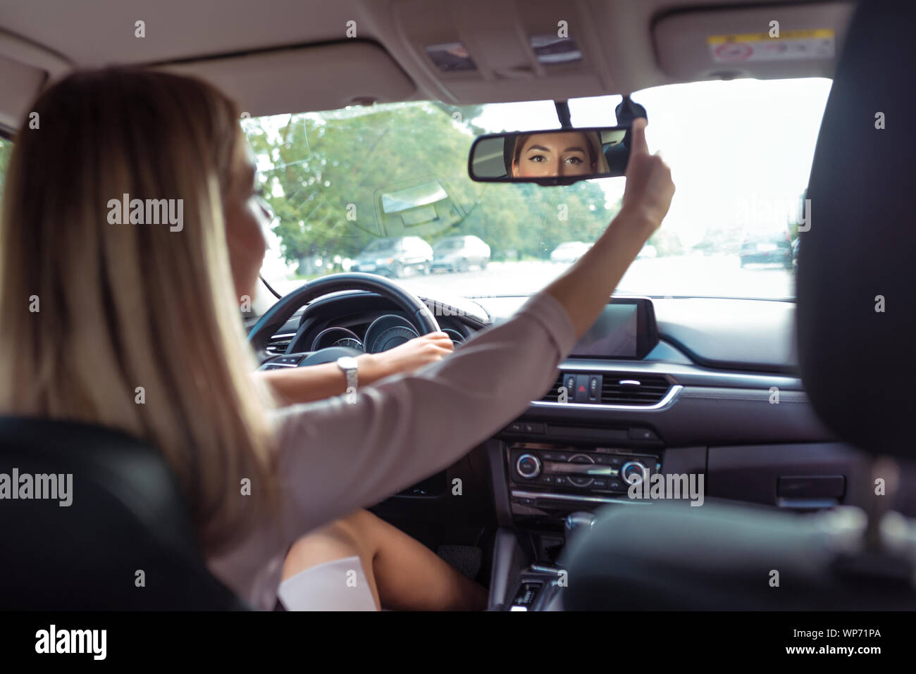 woman driving car, in summer city, rear-view mirror, parking car ...