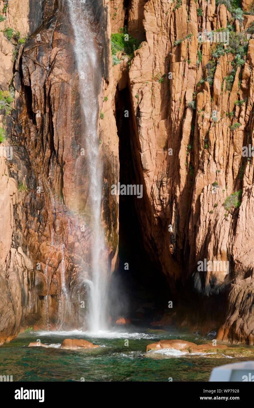Waterfall into green water in front of red rocks Stock Photo - Alamy