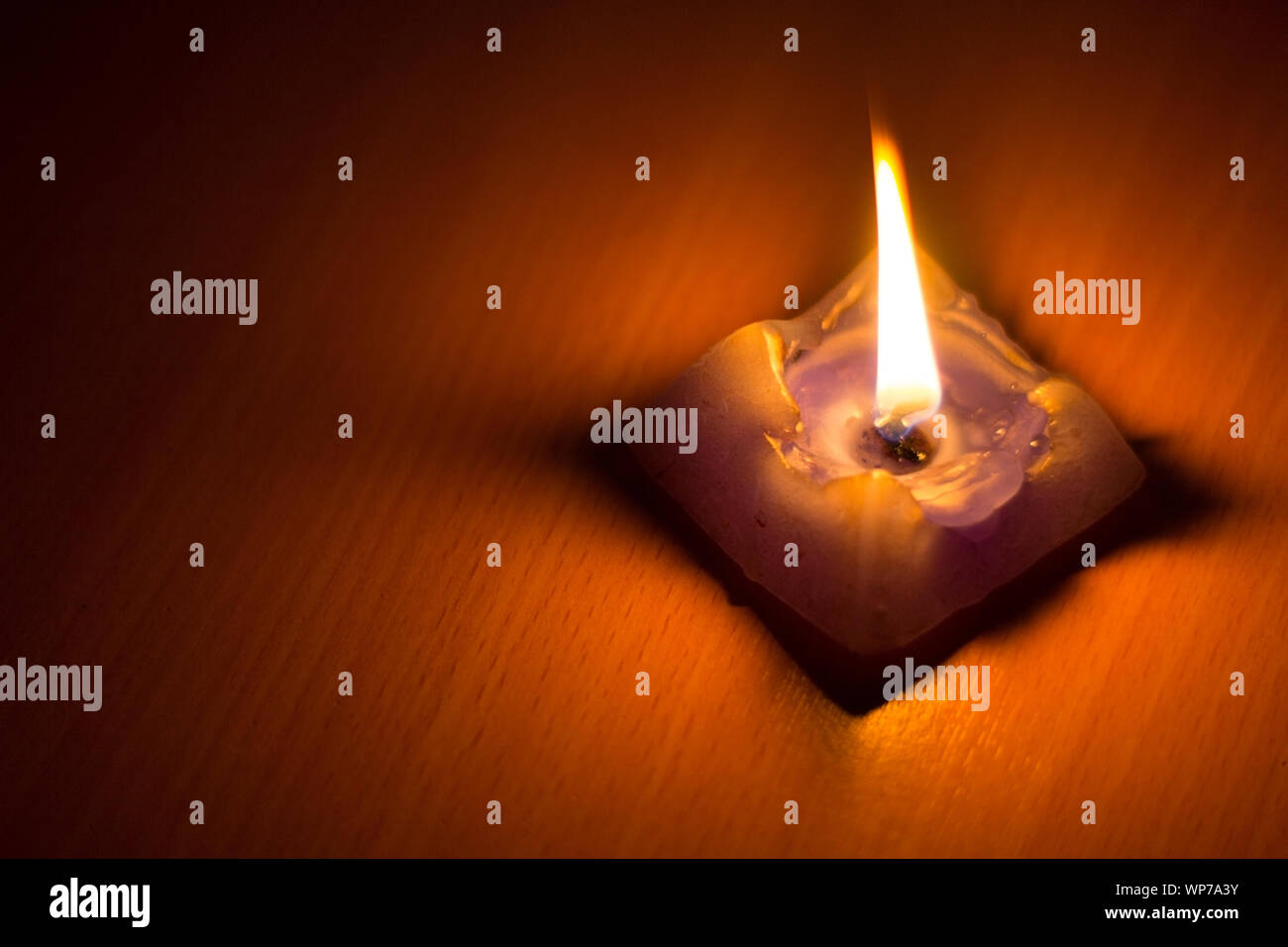Abstract background with a consumed wax candle burning over a wood ...