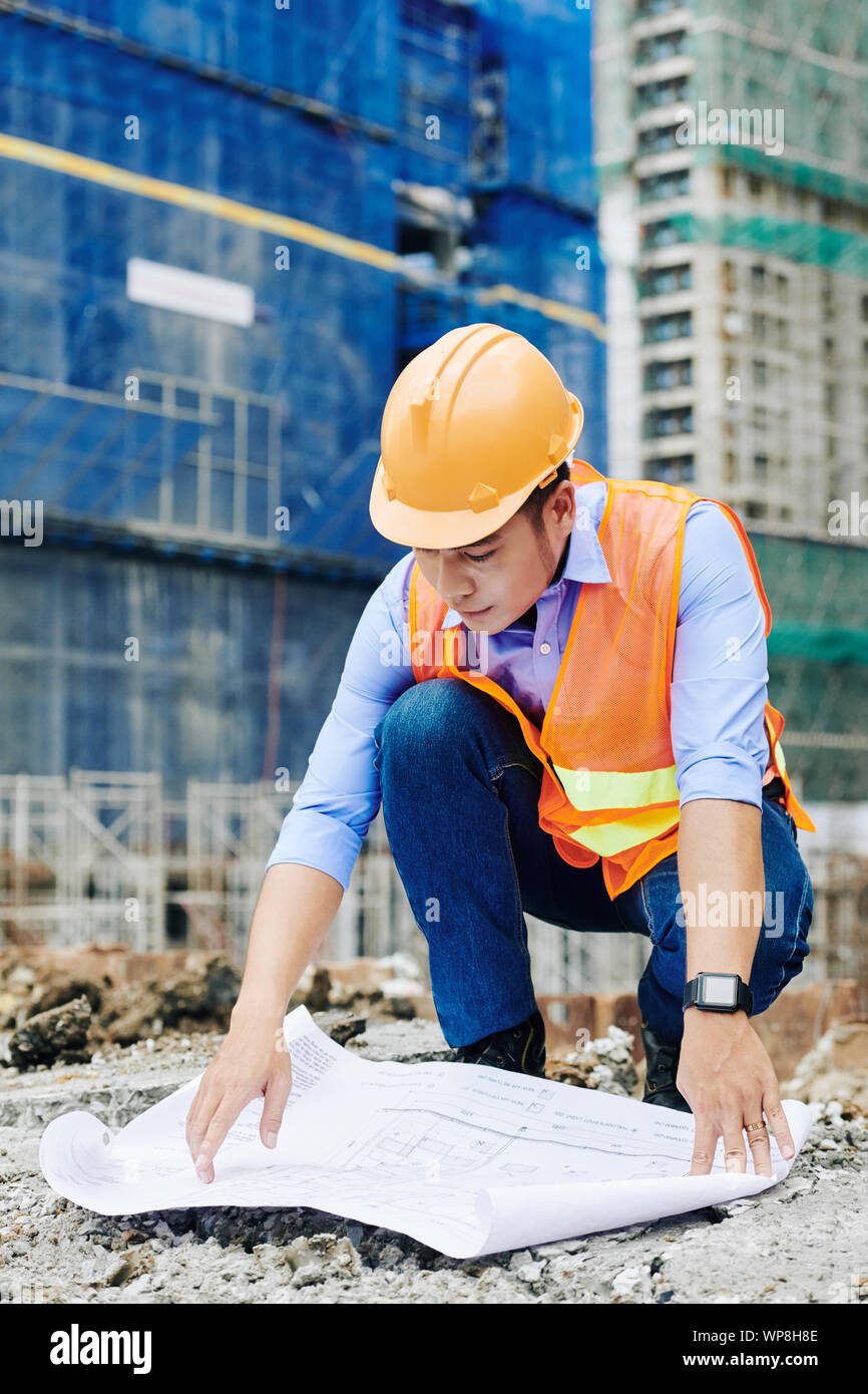 Professional Asian civil engineer spreading out building blueprint on ...