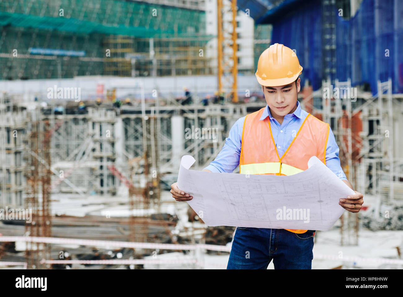 Serious professional Asian civil engineer examining building plan at ...