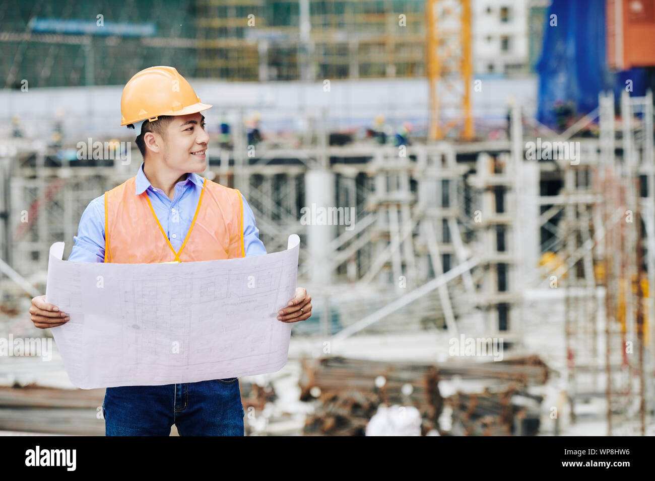 Positive professional Asian civil engineer with building blueprint in ...