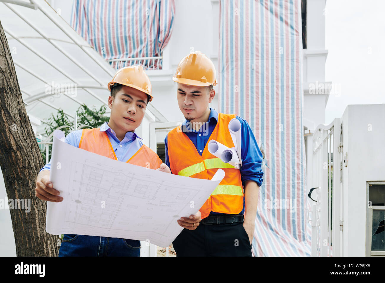 Serious construction workers discussing building layout before ...