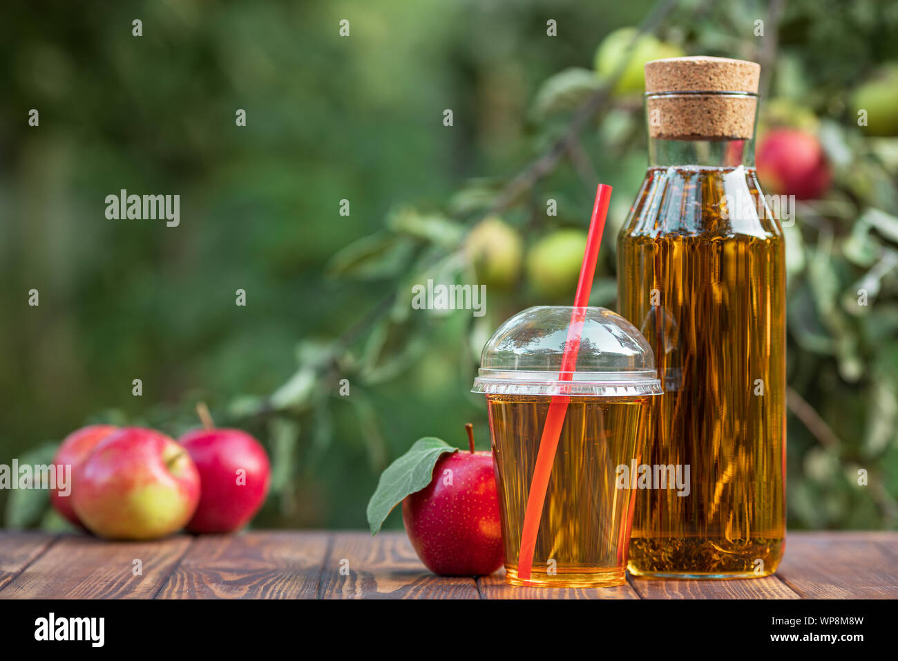apple juice in disposable plastic cup and bottle with ripe fruits on ...