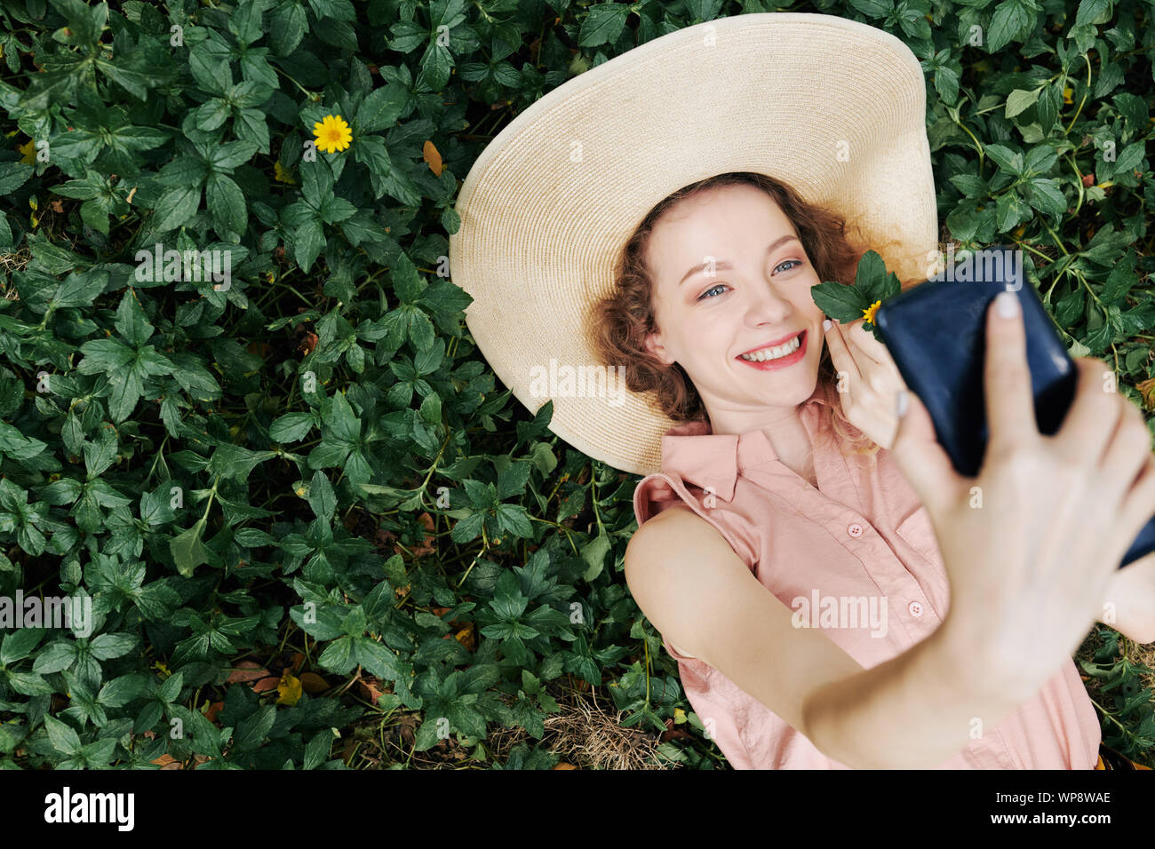 Happy pretty young woman lying on grass and talking selfies on ...