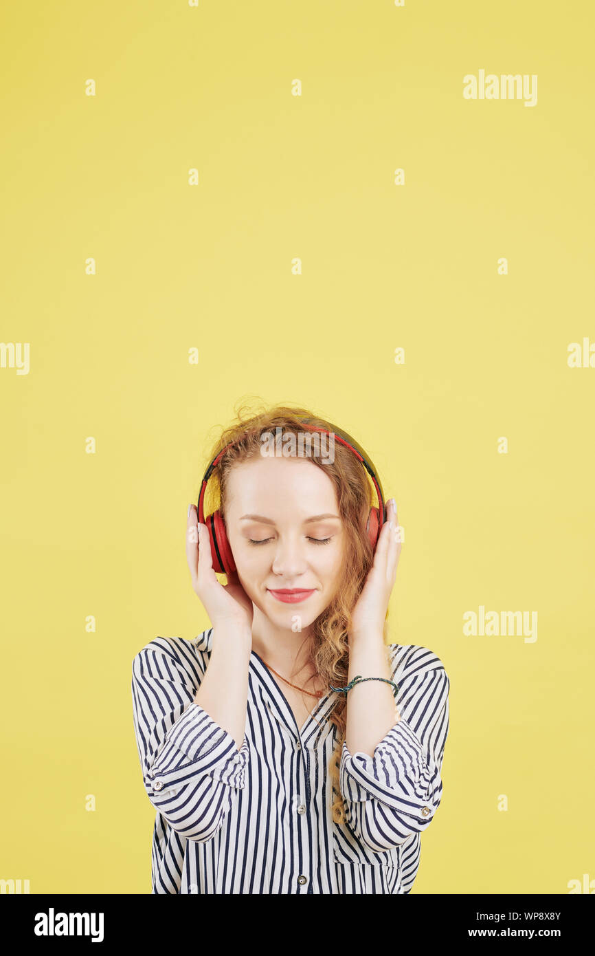 Beautiful young woman closing her eyes and enjoying listening to ...