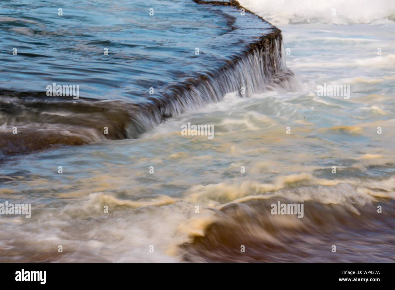 Strong afternoon, incoming tide. Waves are crashing on a tidal pool ...