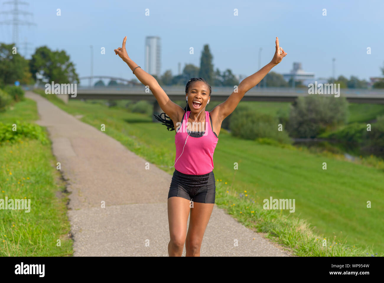 Exuberant young African woman full of vitality running along a rural ...