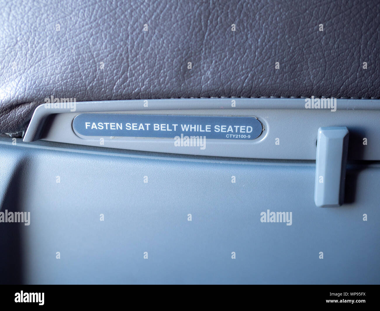Faster seat belt while seated warning posted on back of airline seat ...