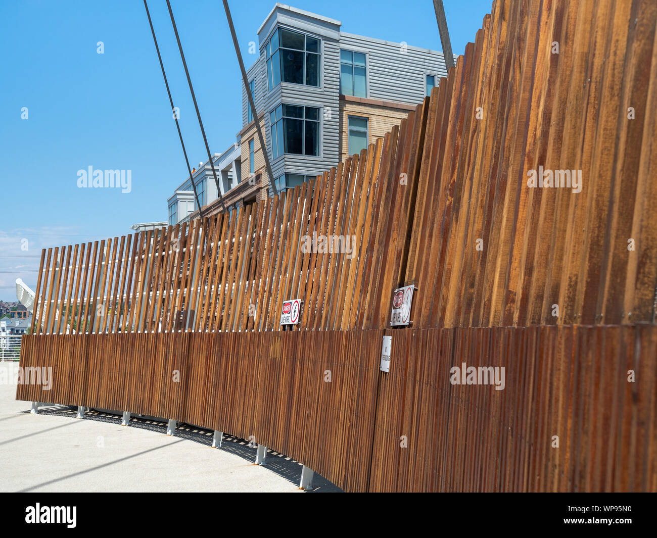 Curved wooden fence with warning signs blocking off dangerous wires ...