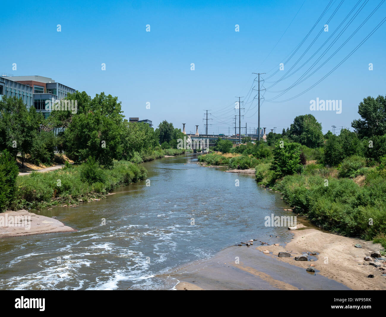 A river canal stream in a populated area with power lines and ...
