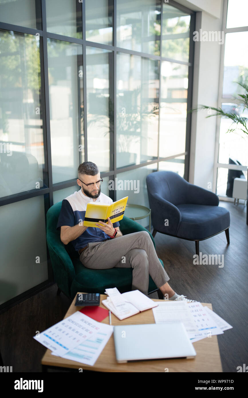 Businessman sitting in armchair and reading book Stock Photo - Alamy