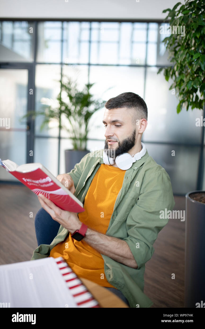 Man sitting in spacious office and reading book while studying Stock ...