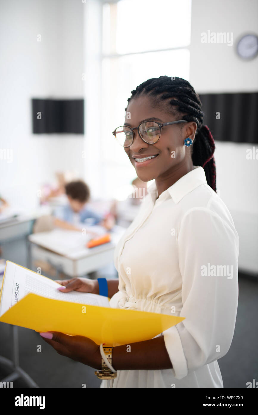Beaming dark-skinned primary school teacher holding notebook Stock ...