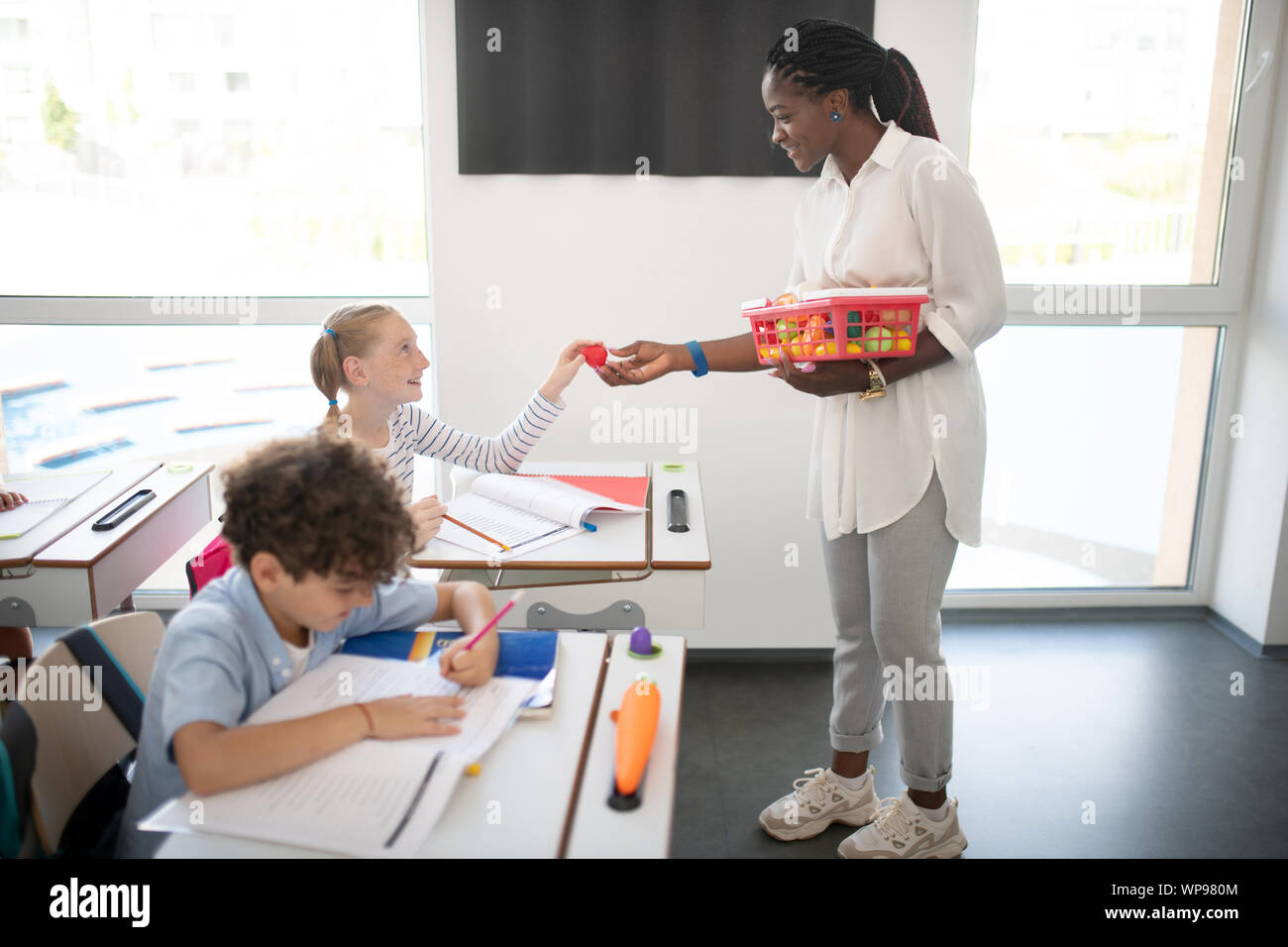 Girl feeling happy while getting little surprise from teacher Stock ...