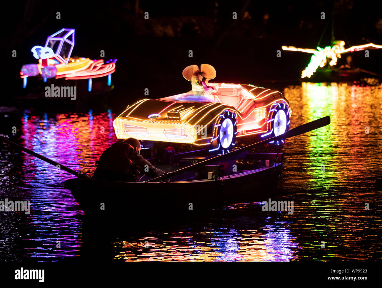 A flotilla of brightly illuminated boats are rowed down the River ...