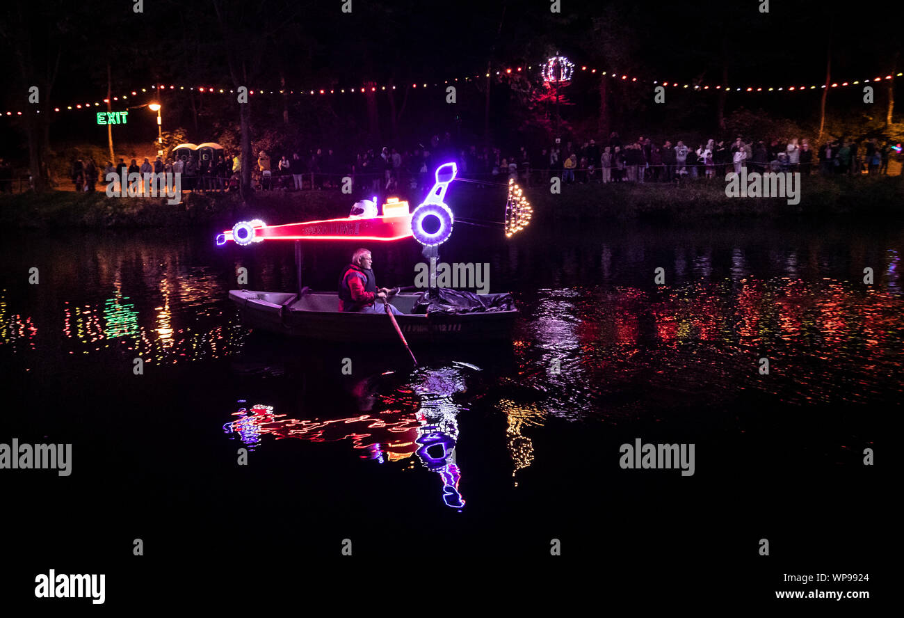 A flotilla of brightly illuminated boats are rowed down the River ...