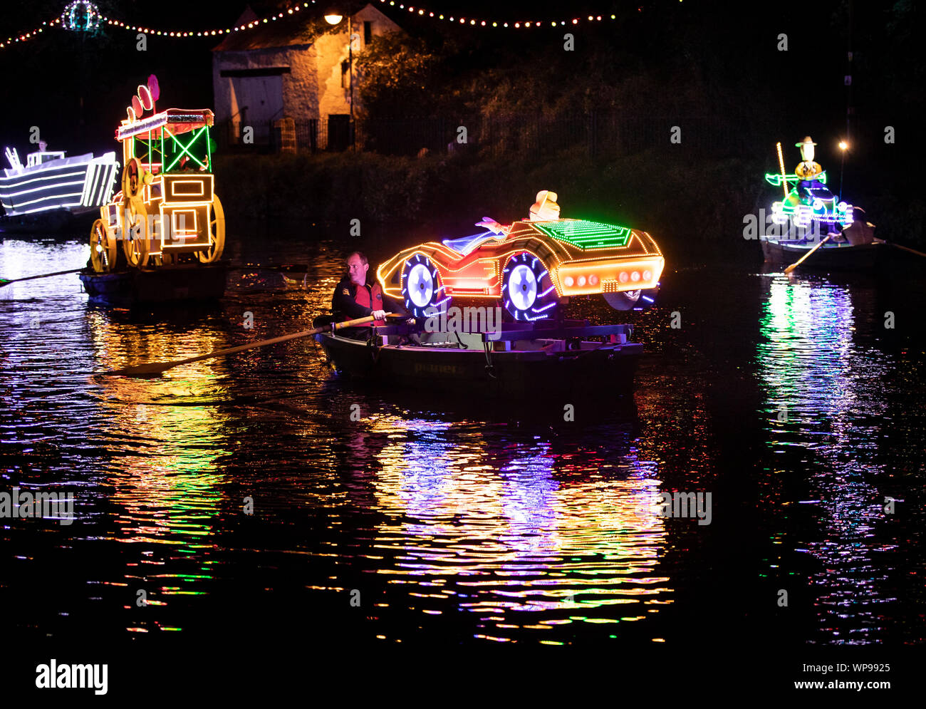 A flotilla of brightly illuminated boats are rowed down the River ...