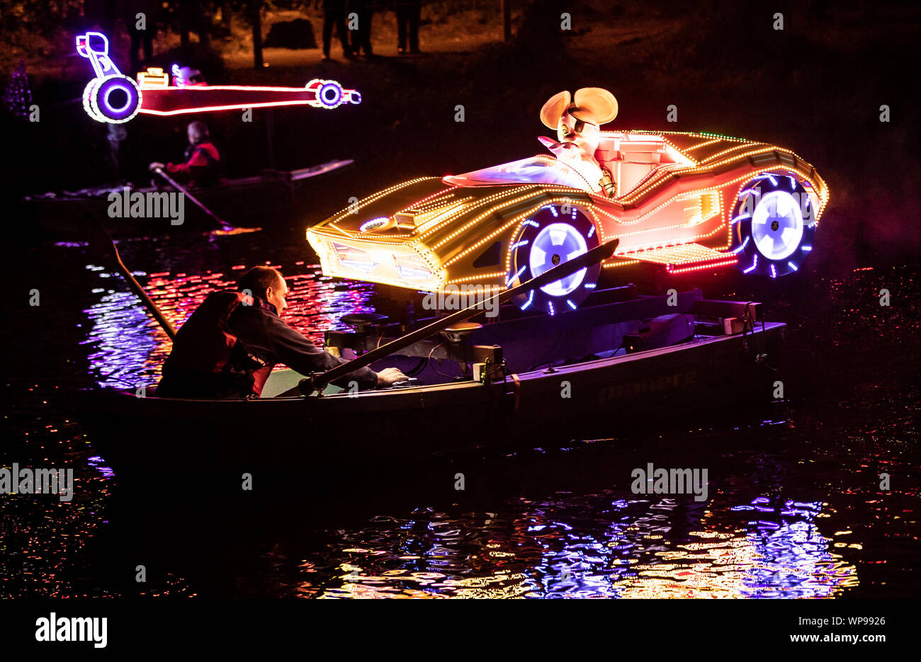 A flotilla of brightly illuminated boats are rowed down the River ...