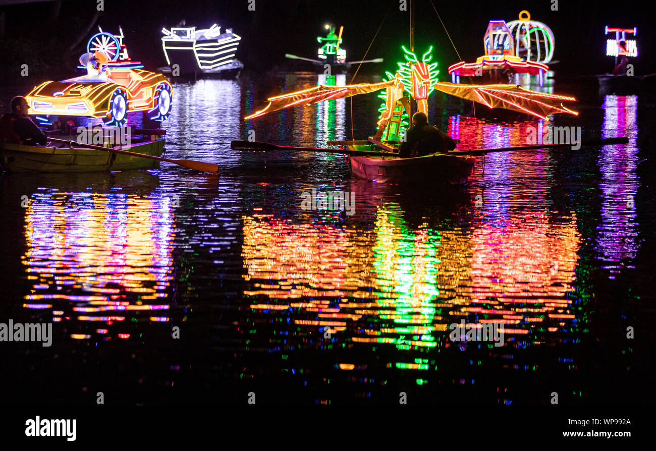 A flotilla of brightly illuminated boats are rowed down the River ...