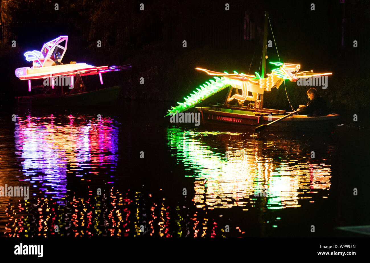 A flotilla of brightly illuminated boats are rowed down the River ...