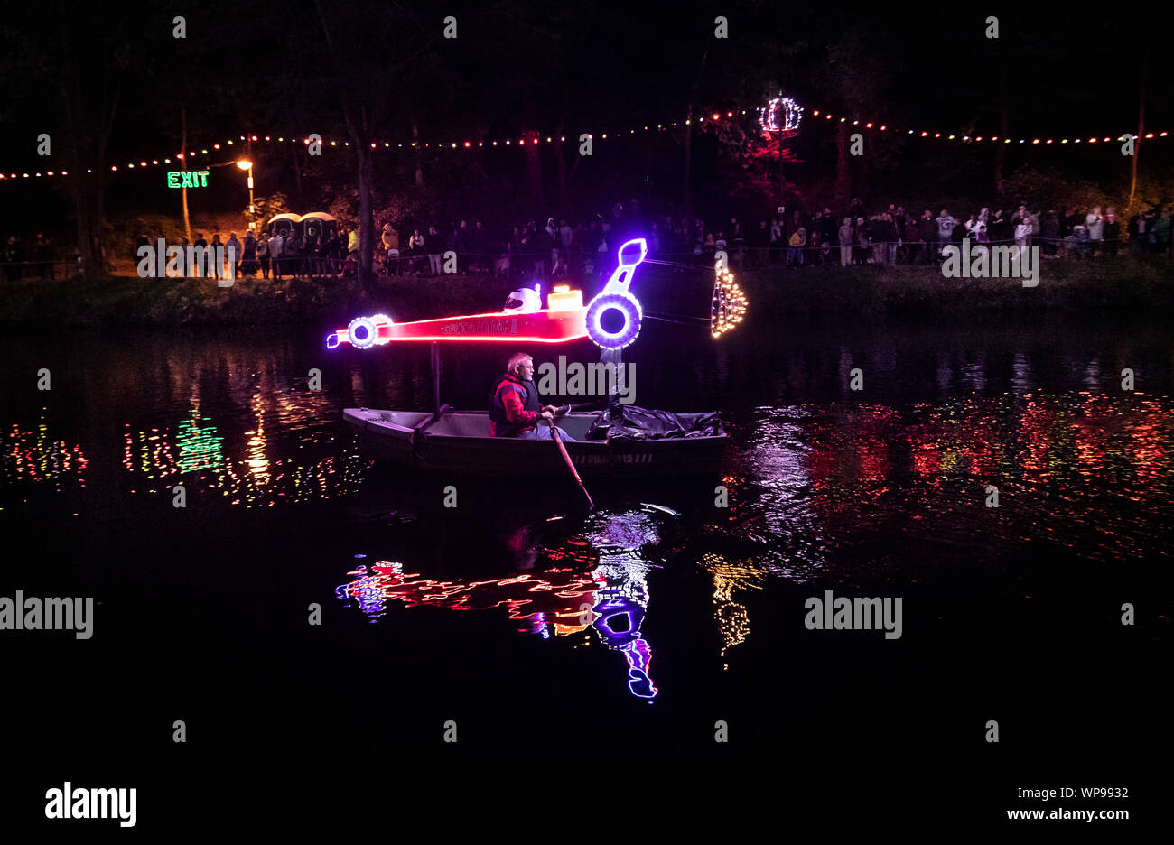 A flotilla of brightly illuminated boats are rowed down the River ...