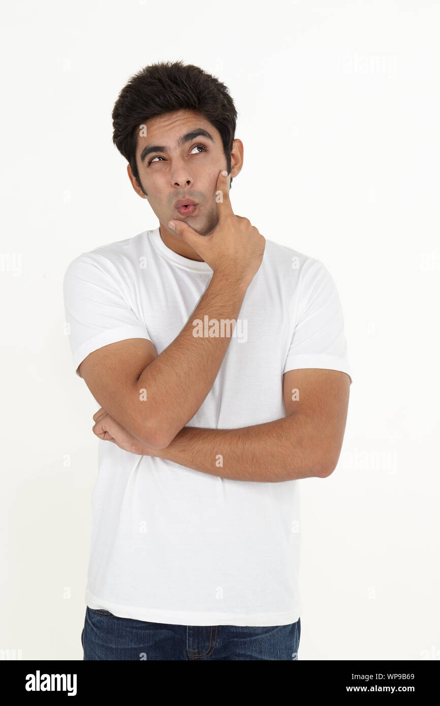 Young man thinking with his hands on chin Stock Photo - Alamy