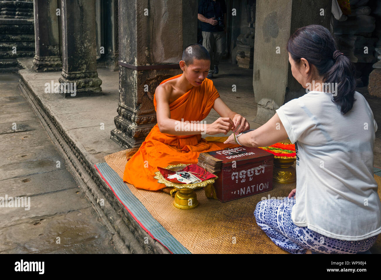 monk blessing Buddhist people in Central courtyard inside Angkor Wat ...