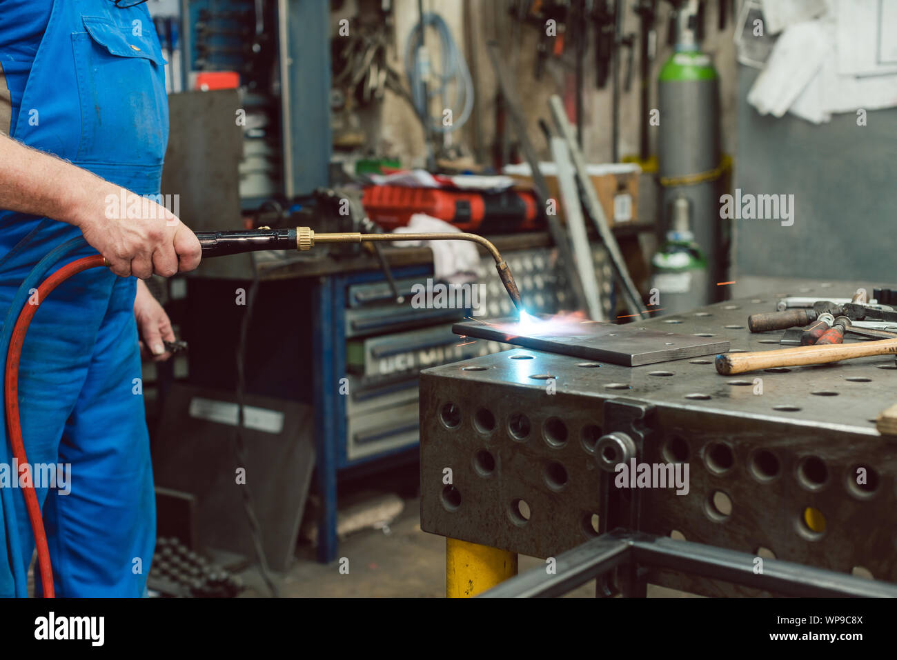 Metalworker heating up piece of metal with burner Stock Photo - Alamy