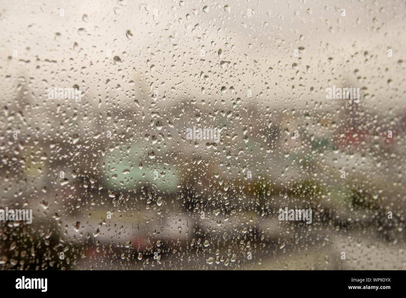 rain drop on clear glass window, reflection of blurred city and light ...