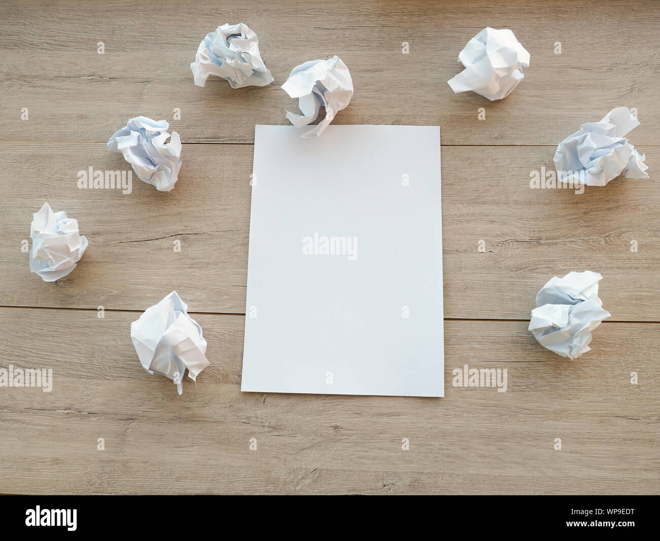 Writing concept - crumpled up paper wads with a sheet of white paper ...